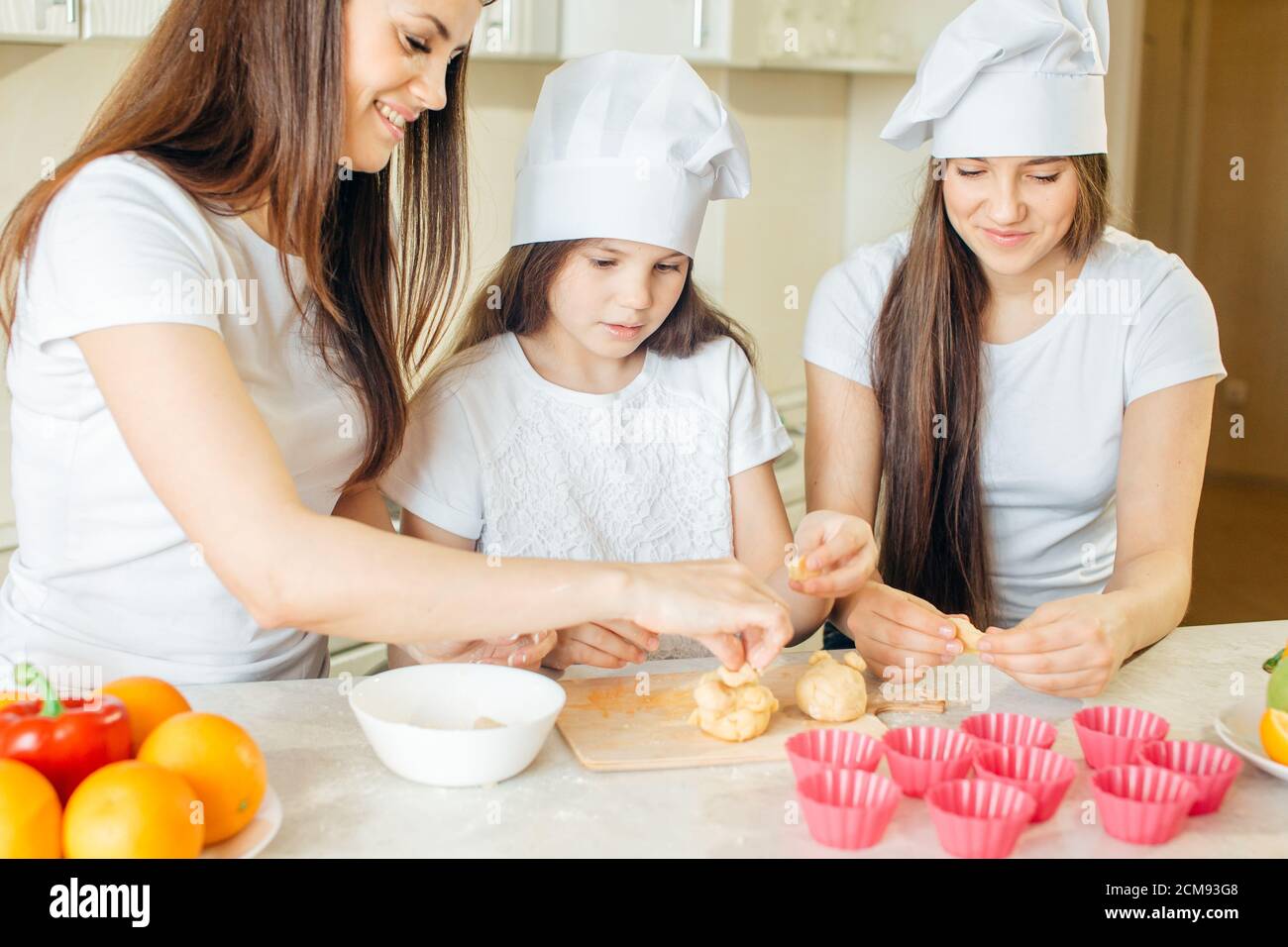 two sisters cooking with her mother in the kitchen. Infant Chef Concept ...