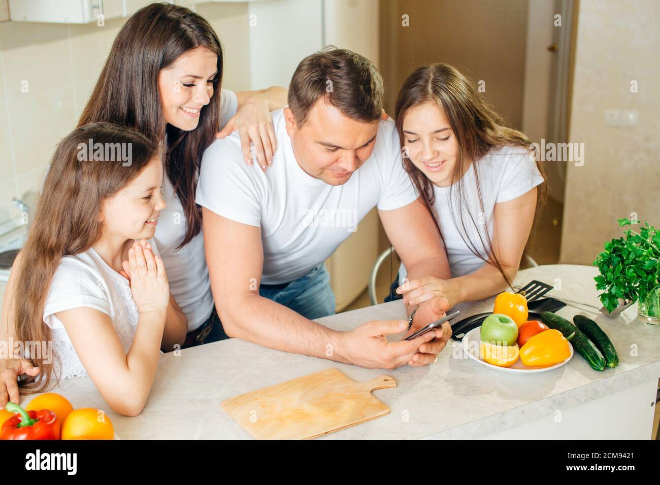 family using cell phone while cooking at kitchen Stock Photo - Alamy