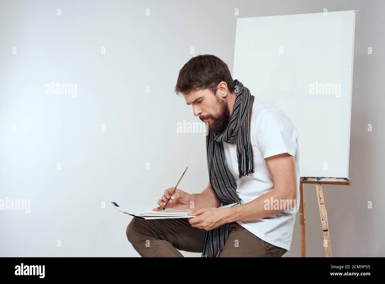 Male artist sitting on chair drawing brush easel hobby Creative light ...