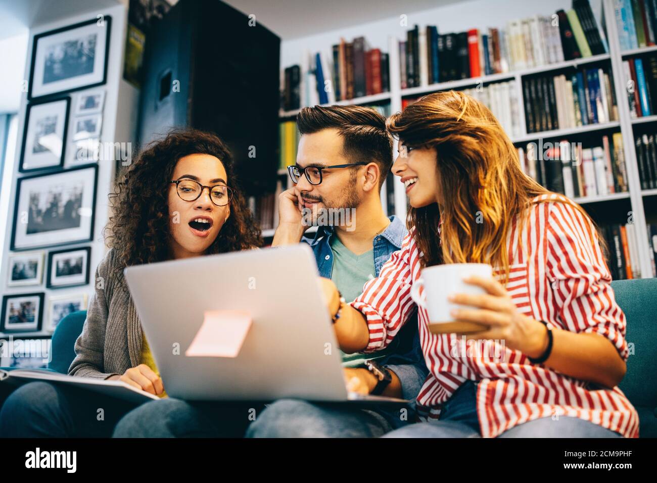 Group of happy students reading books and preparing to exam in library ...