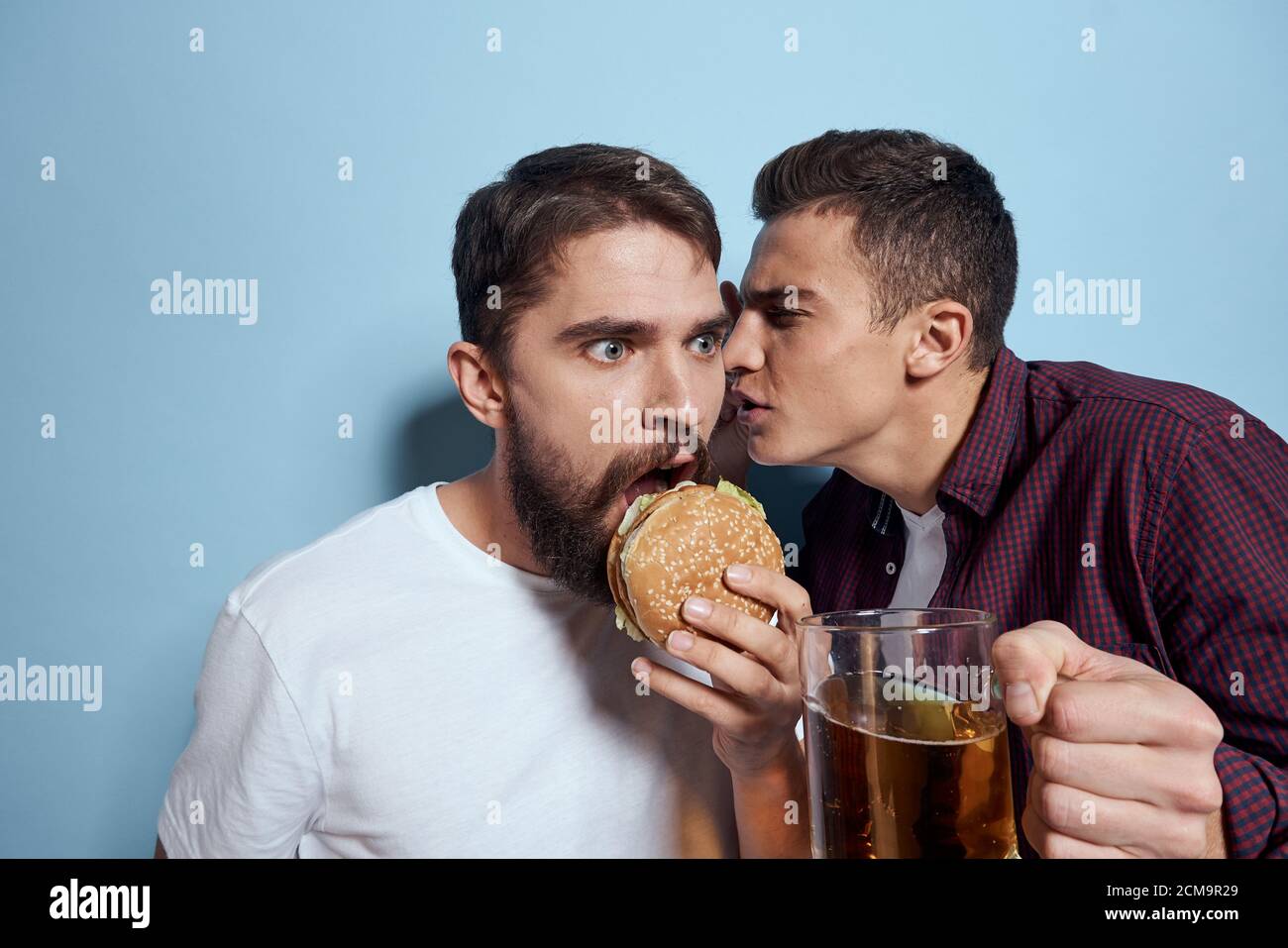 Two cheerful drunk friends drinking beer lifestyle emotions on a blue ...