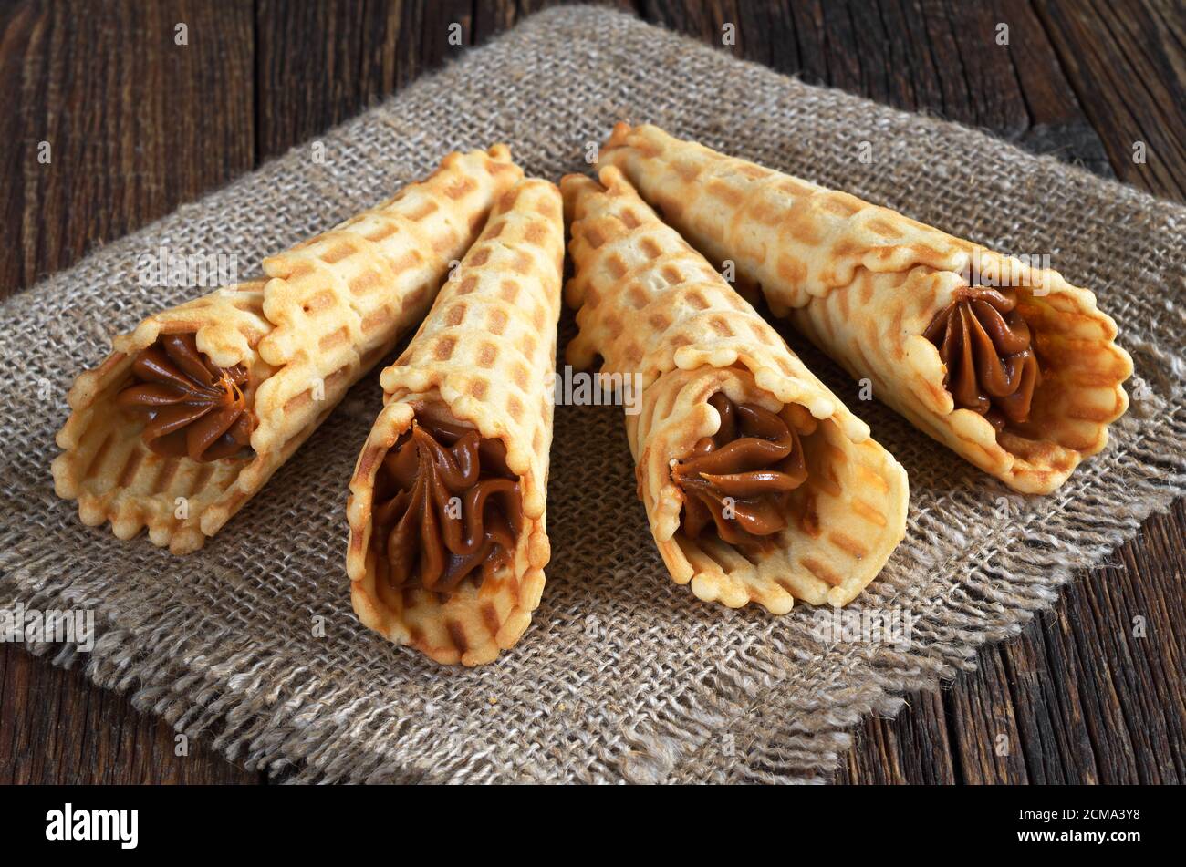 Waffle cones with sweet boiled condensed milk on rustic wooden table ...