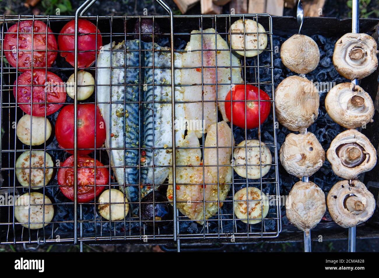 bbq concept fish on fire with mushroom and tomatoes Stock Photo - Alamy