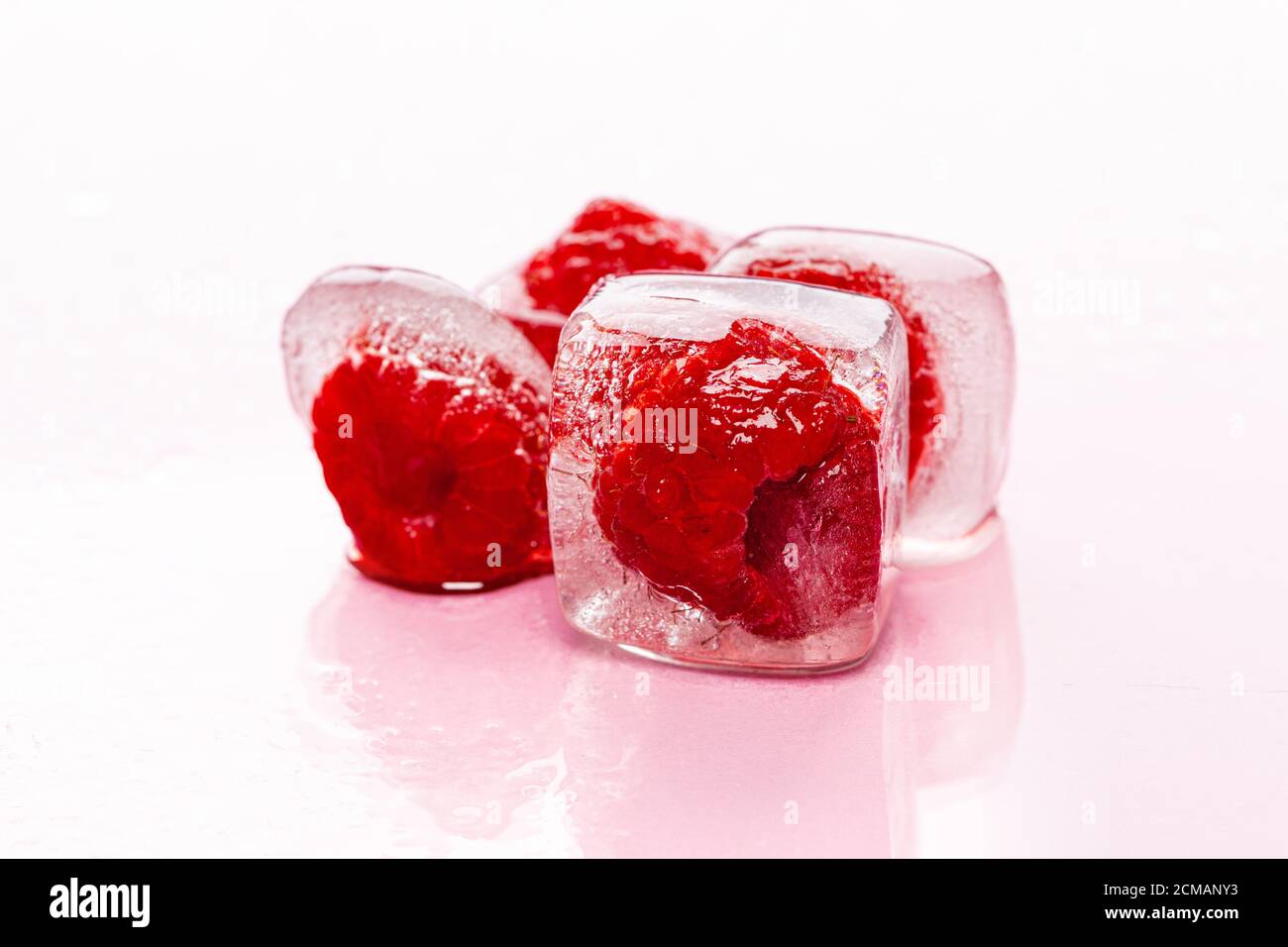 Raspberry ice cubes on pink glossy background Stock Photo - Alamy