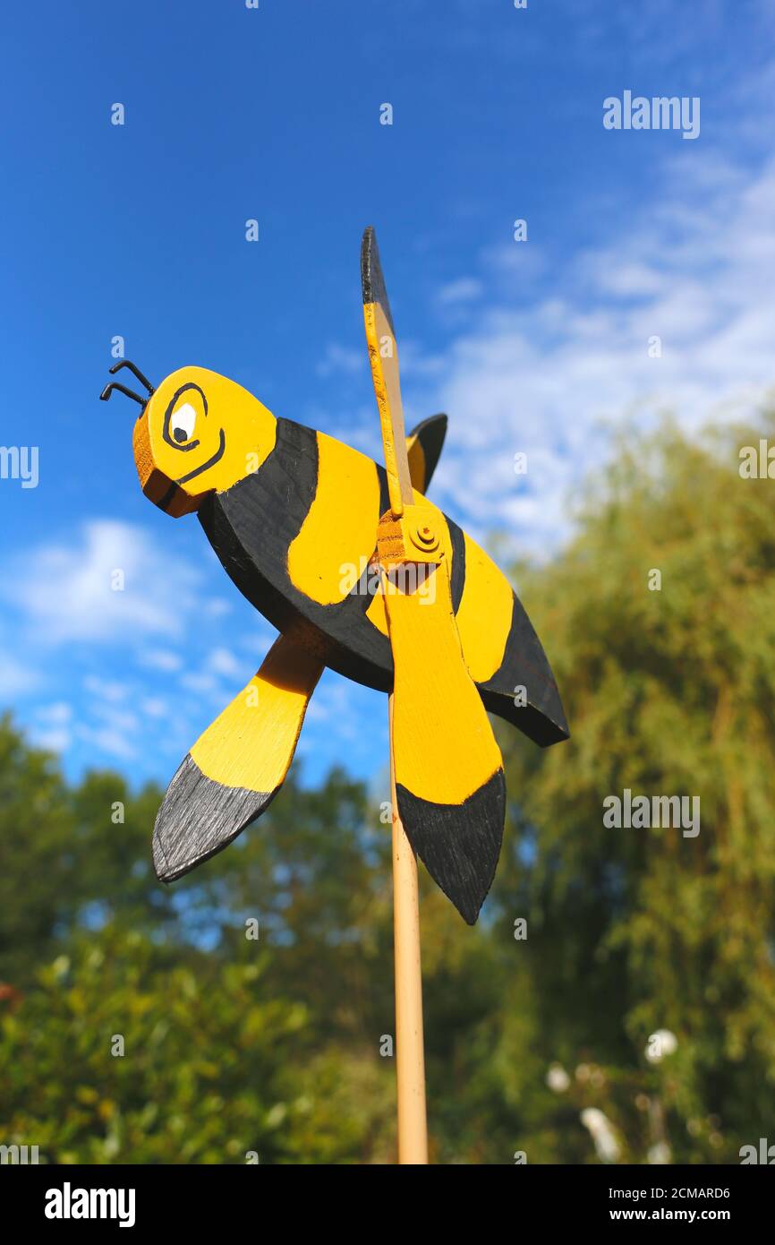 Black and yellow whirligig wind spinner in the shape of a wasp in a ...