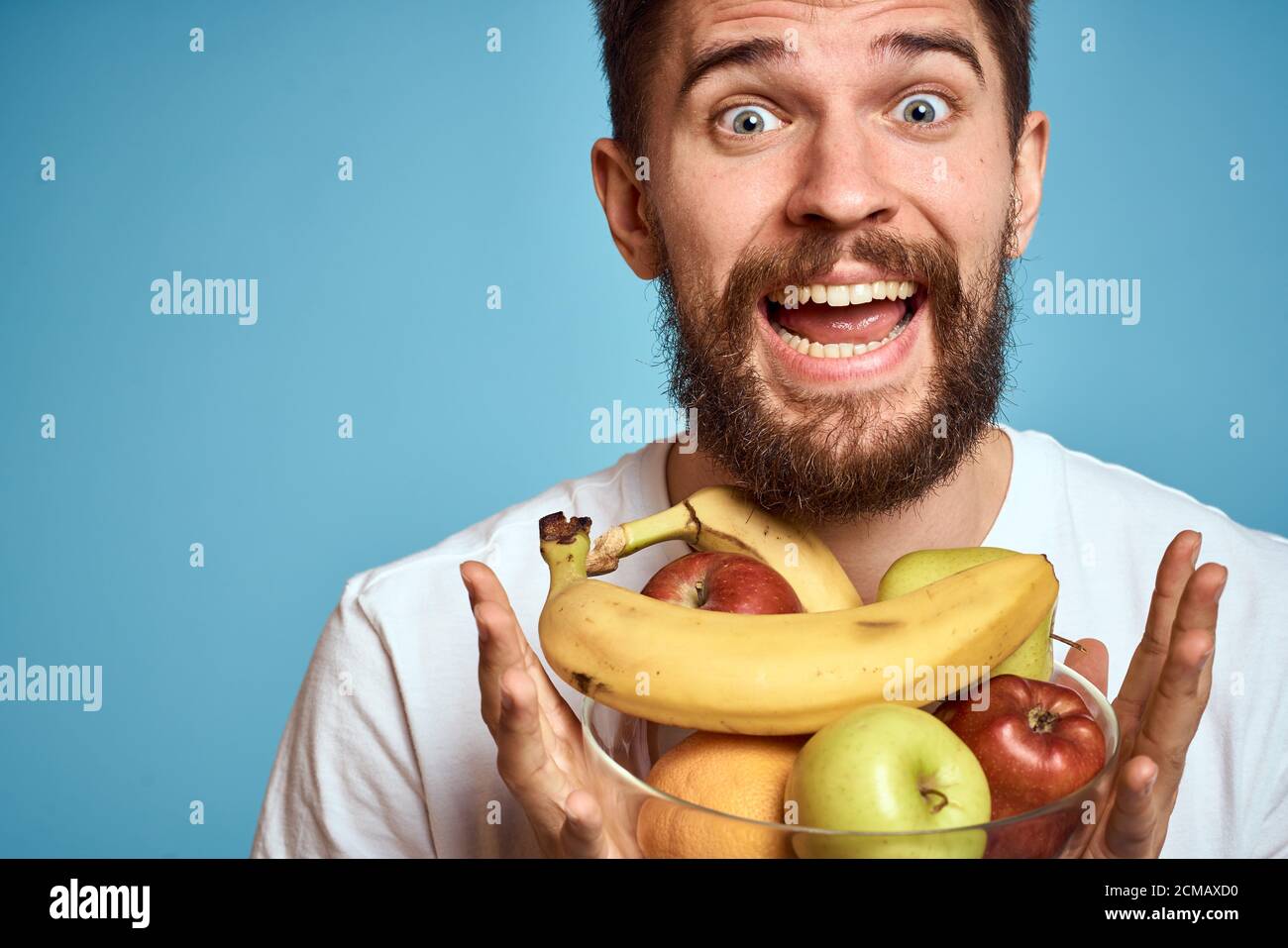 dark background handsome man with a beard holding fresh fruit and ...