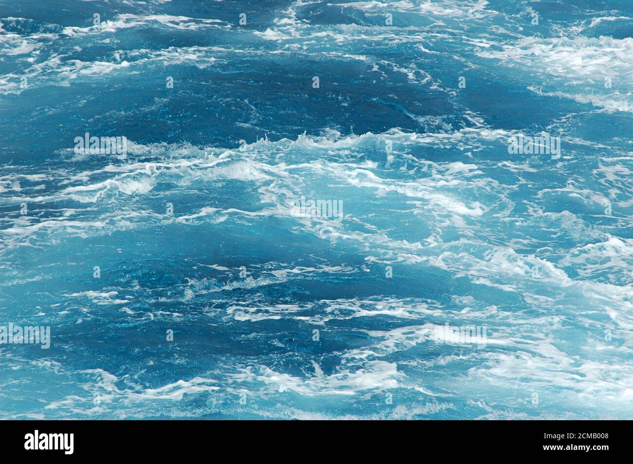 Frothy wakes created by a small boat trace on the water surface ...
