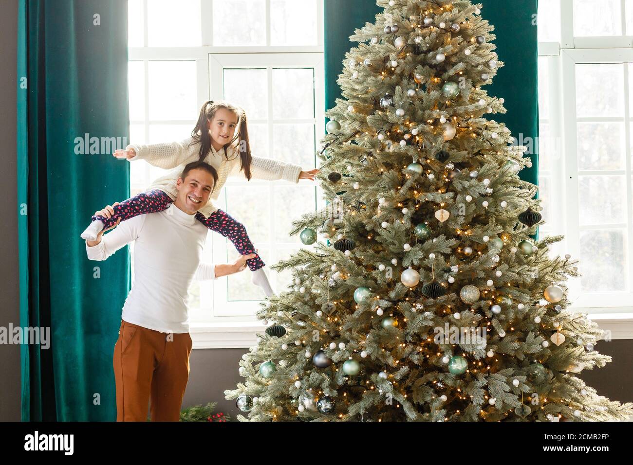 Happy father and his little daughter decorating the Christmas tree at ...