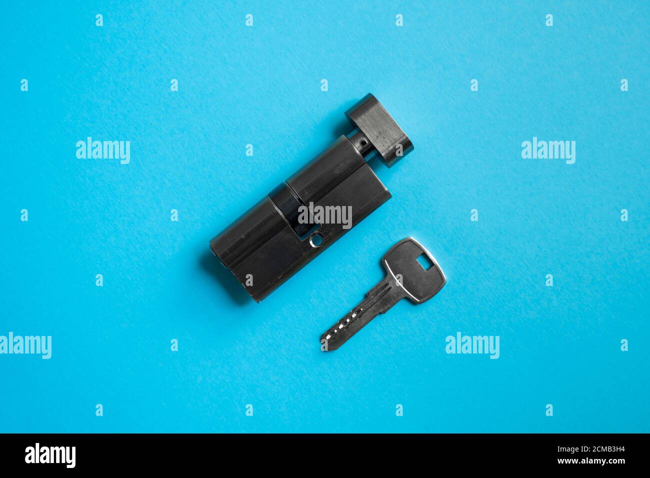 A door lock cylinder core with key on the blue background. The cylinder ...