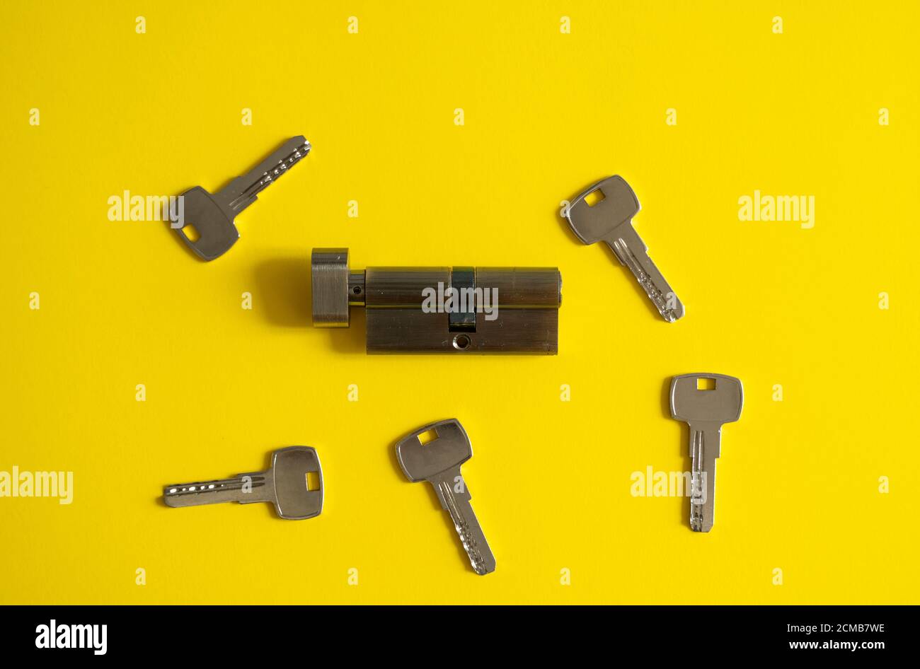 A door lock cylinder core with keys on the yellow background. The ...