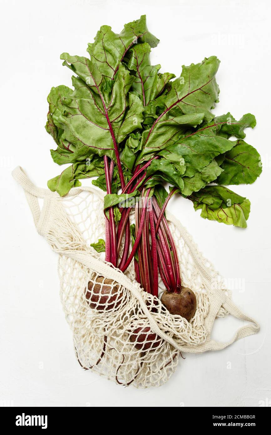 Trendy string bag with fresh young beetroot and haulm over light white ...