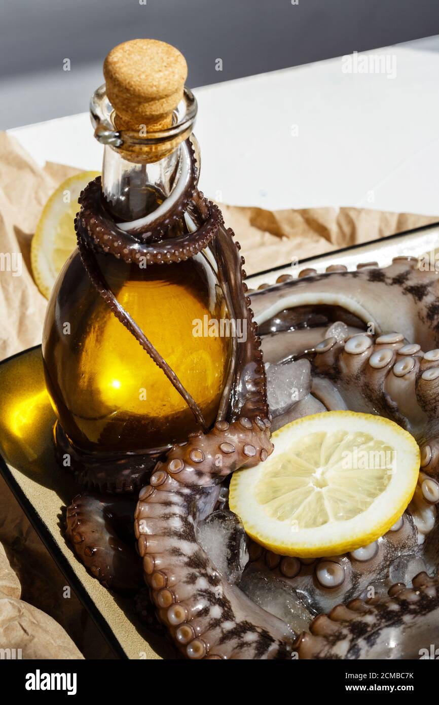 Seafood, olive oil with raw octopus on a plate with lemons ready for ...