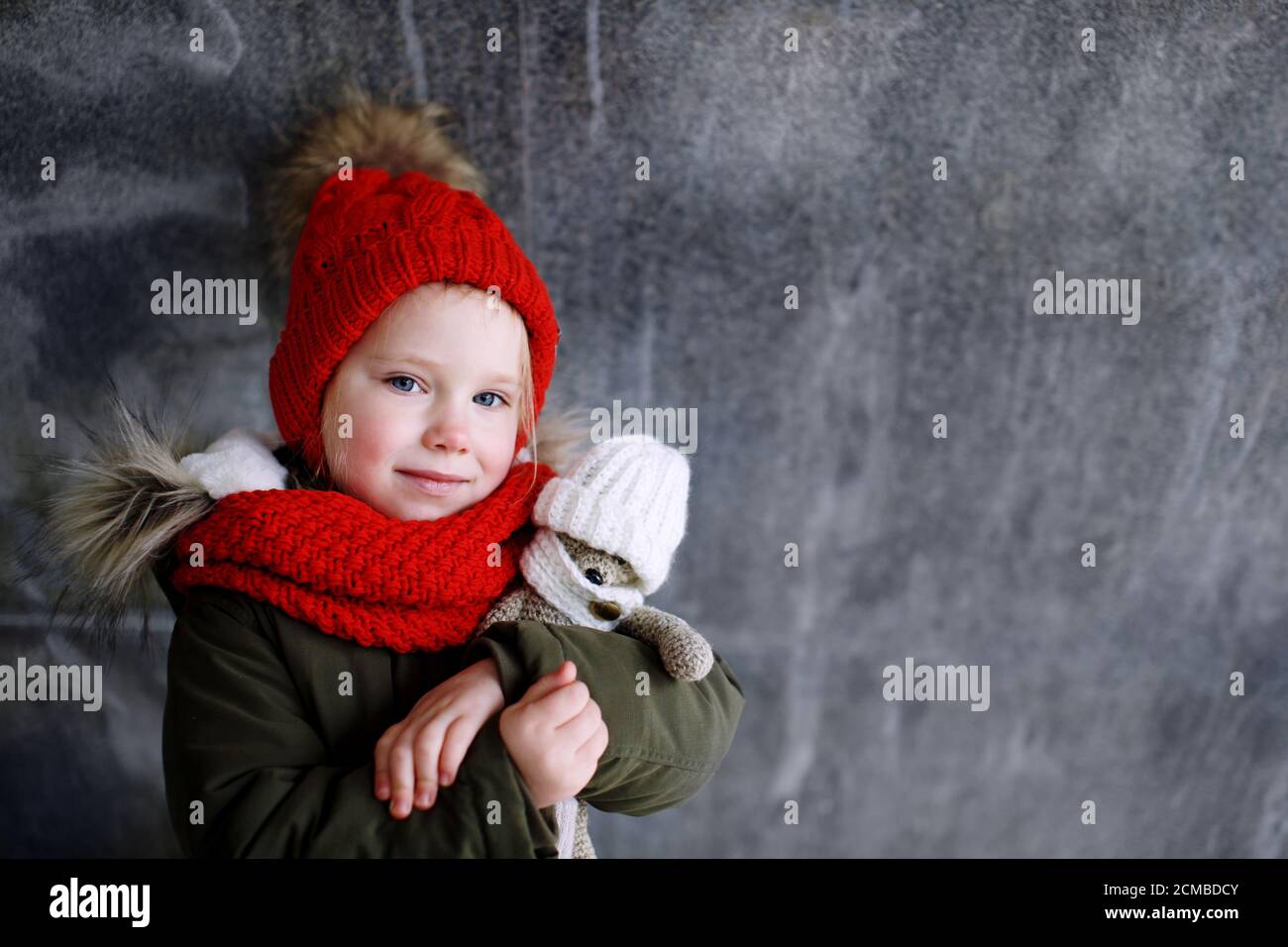Close-up portrait of a cute little kid girl in a red hat and scarf ...