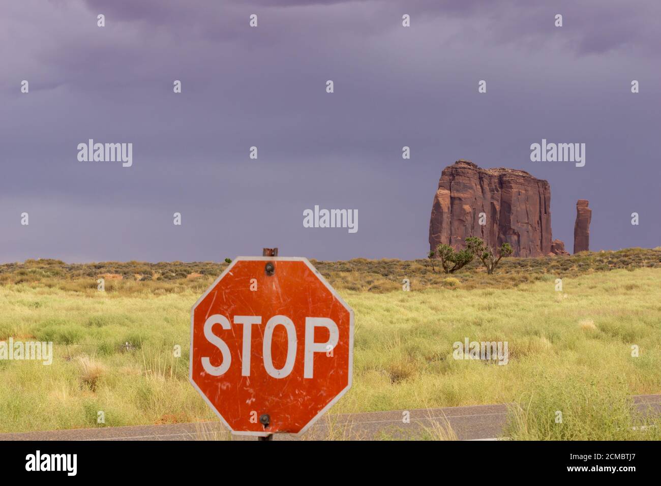 Sunlight highlights flat land and grass with sharp rock outcrop beyond ...