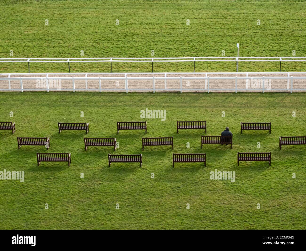 One man sat alone in a group of benches watching the horse racing Stock ...