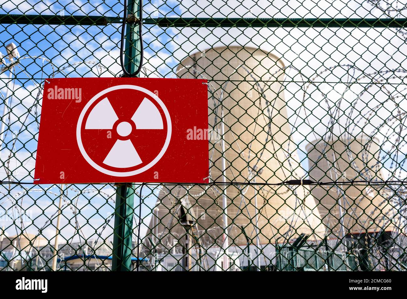 A radioactivity warning sign on the security fence with barbed wire of ...
