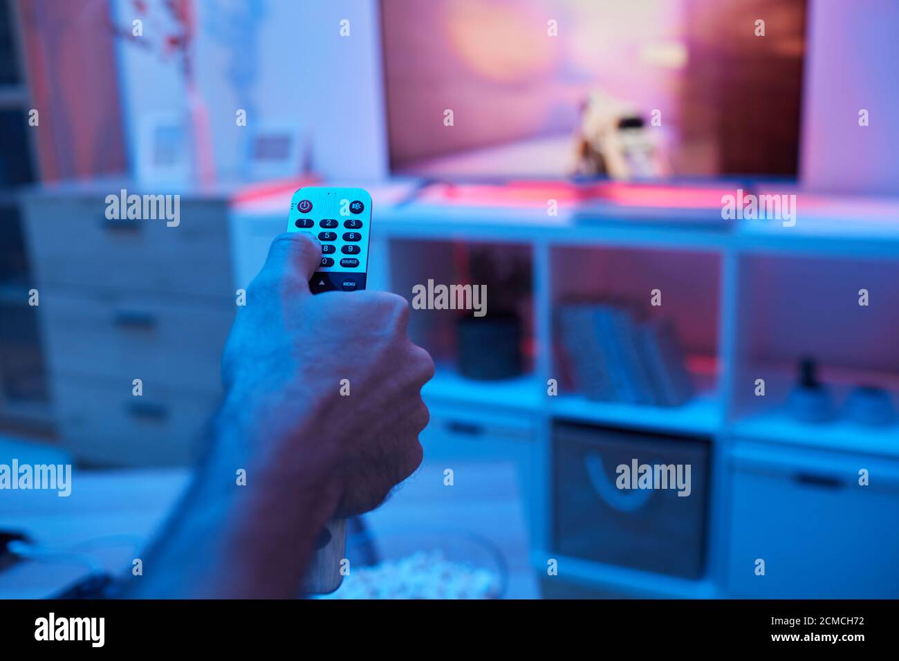 Close-up of man using remote control and changing the channels during ...