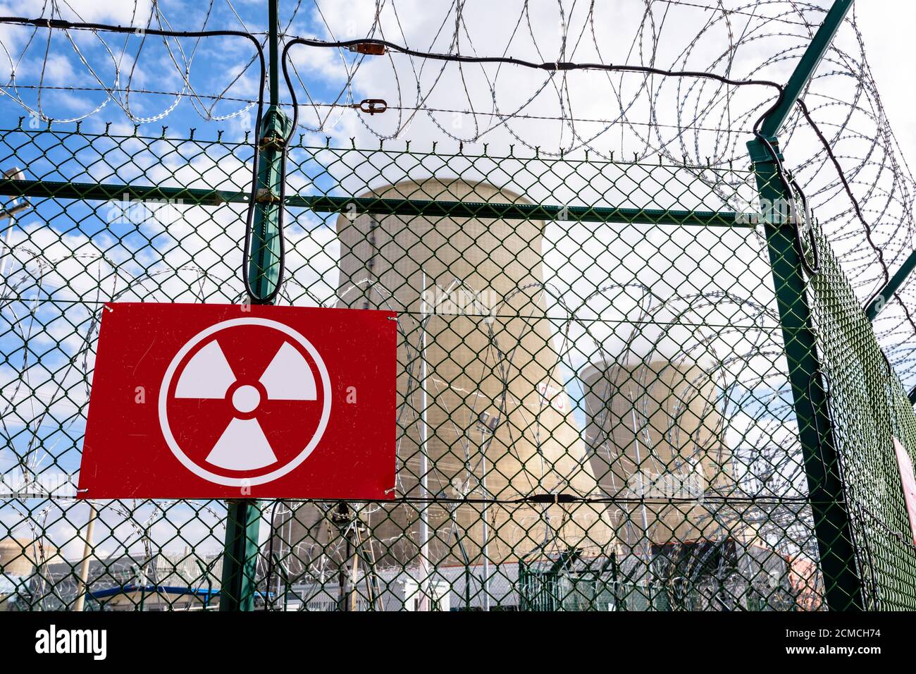 A radioactivity warning sign on the security fence with barbed wire of ...