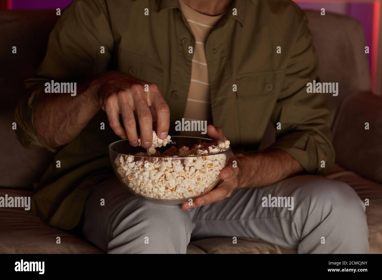 Close-up of man eating popcorn on the sofa during watching TV Stock ...