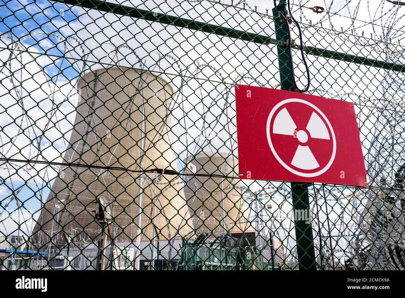 A radioactivity warning sign on the security fence with barbed wire of ...