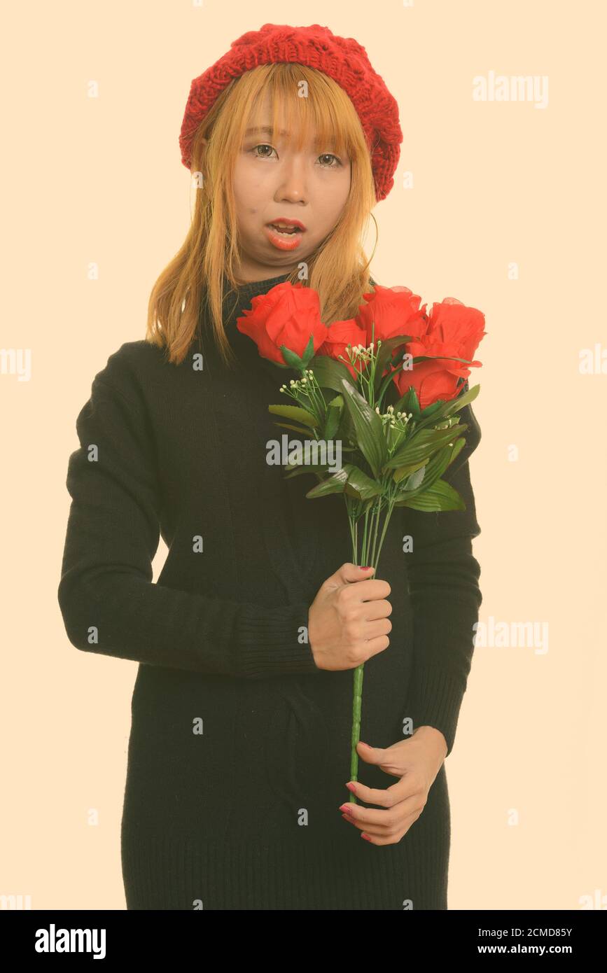 Young cute Asian woman holding red roses looking shocked Stock Photo ...