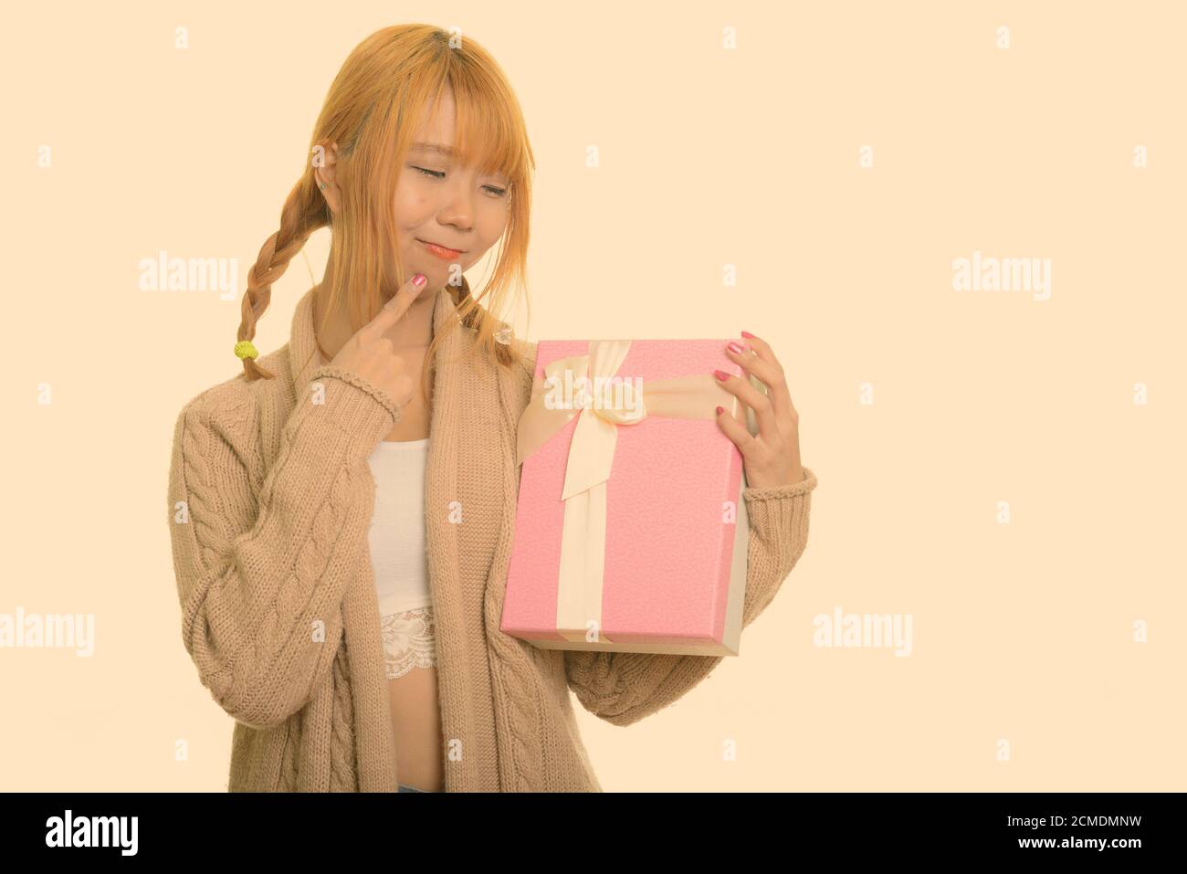 Young cute Asian woman holding gift box while thinking Stock Photo - Alamy