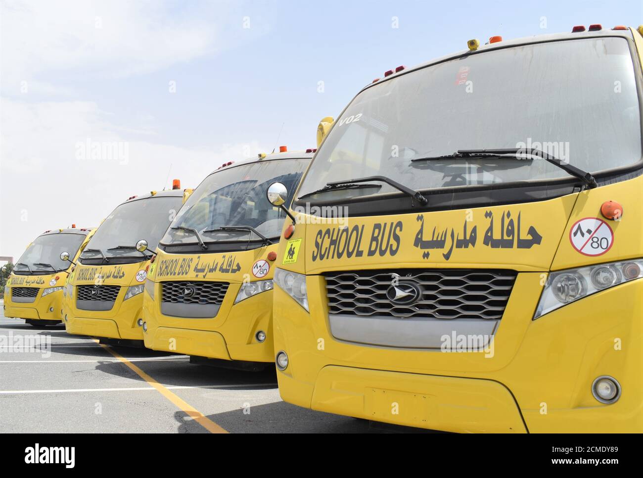A row of yellow school buses parked in a car park in Dubai waiting for ...