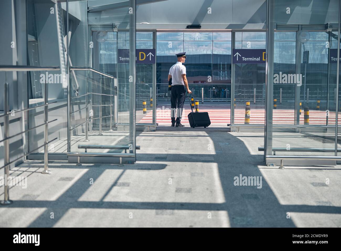Male pilot with travel suitcase standing outside airport terminal Stock ...