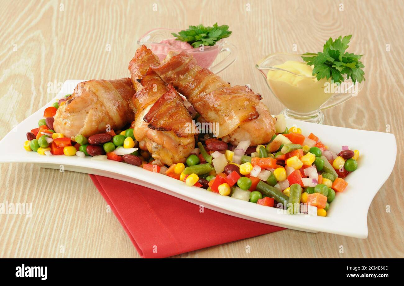 Roast chicken leg wrapped in bacon with vegetables and sauces Stock ...