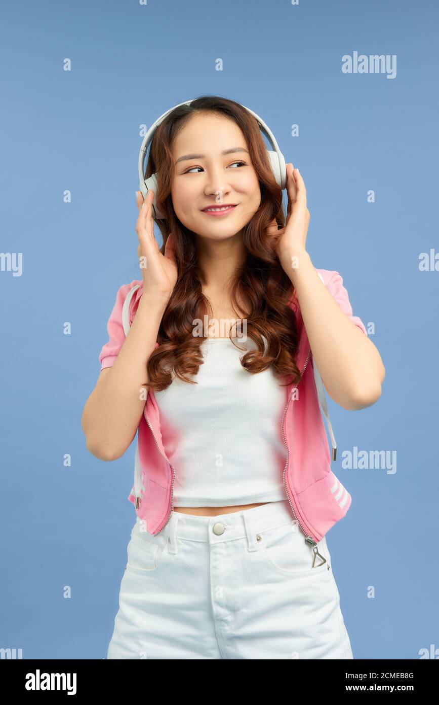 Pretty Cool Girl Having Fun And Listens To Music In The Headphones Dancing Over Blue Background