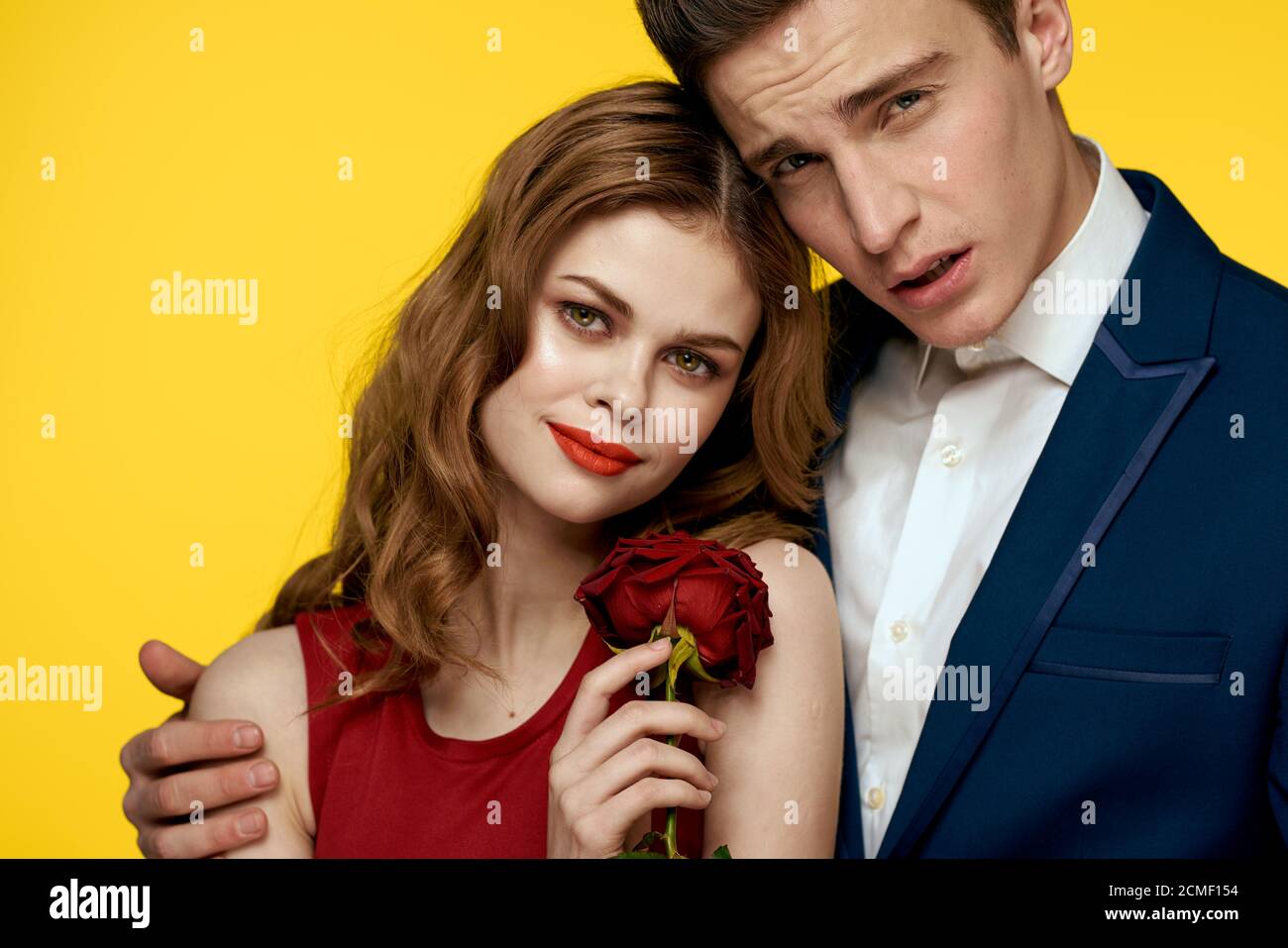 A romantic man hugs a woman in a red dress with a rose in his hand on a ...