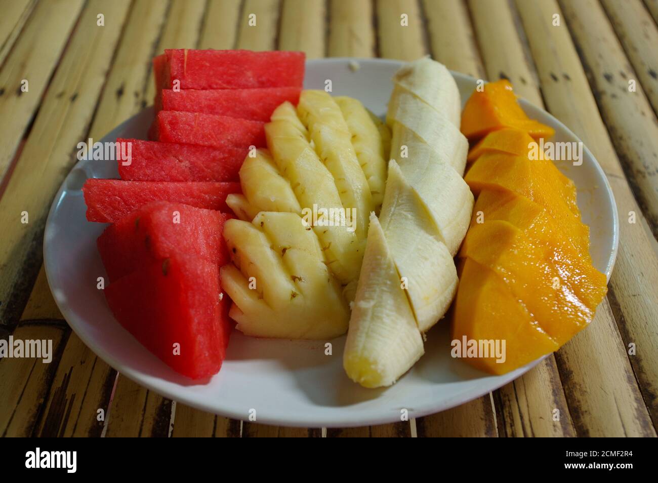 white plate with sliced fruit: watermelon, mango, banana, pineapple ...