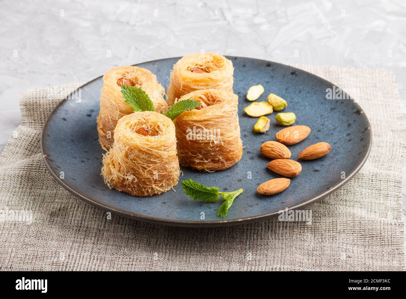 Kunafa, traditional arabic sweets in blue ceramic plate on a gray ...