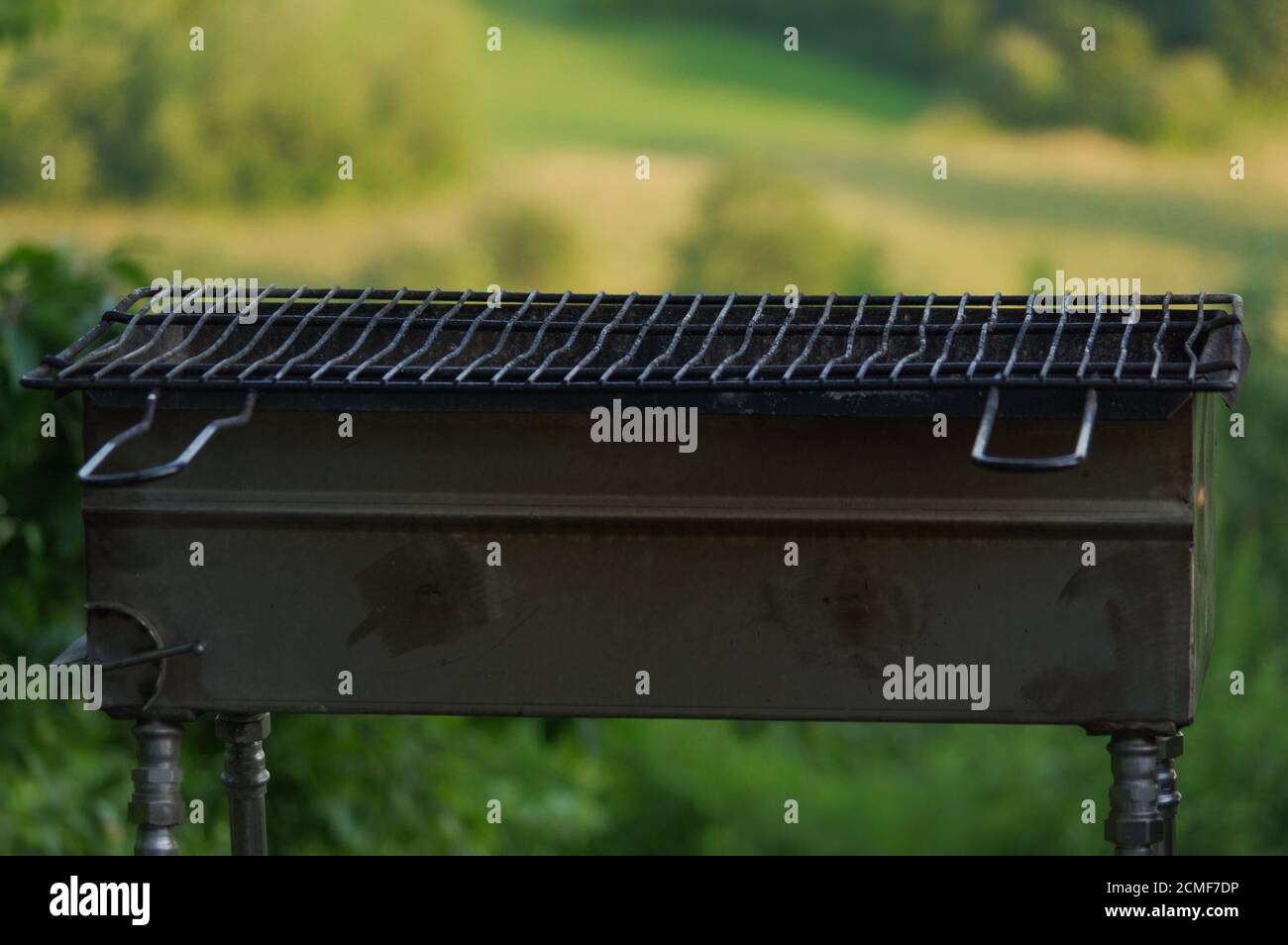 Empty portable BBQ grill in front of a fresh green summer landscape ...