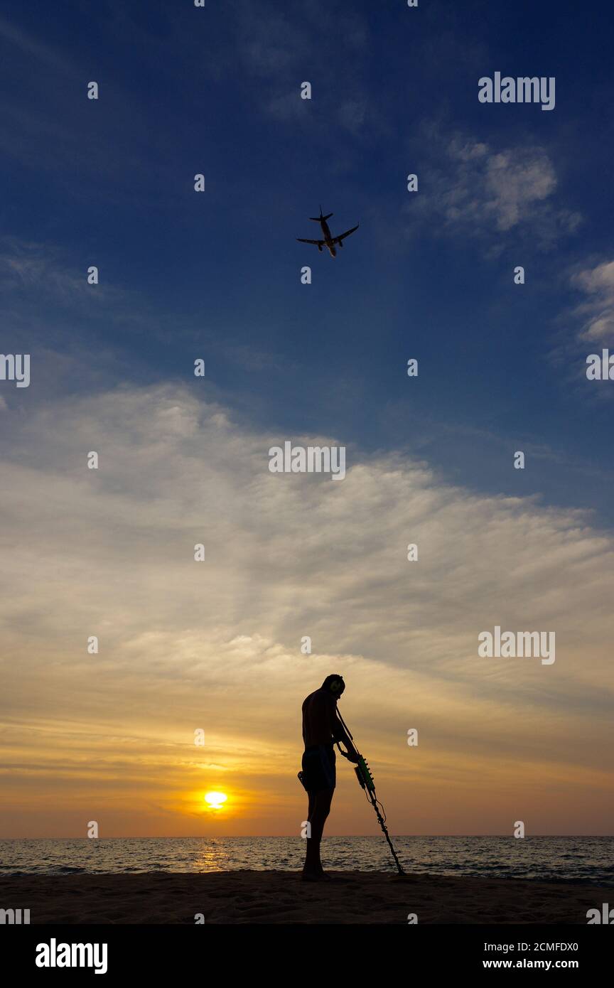 Treasure hunter with Metal detector on the sunset the beach, a plan in ...