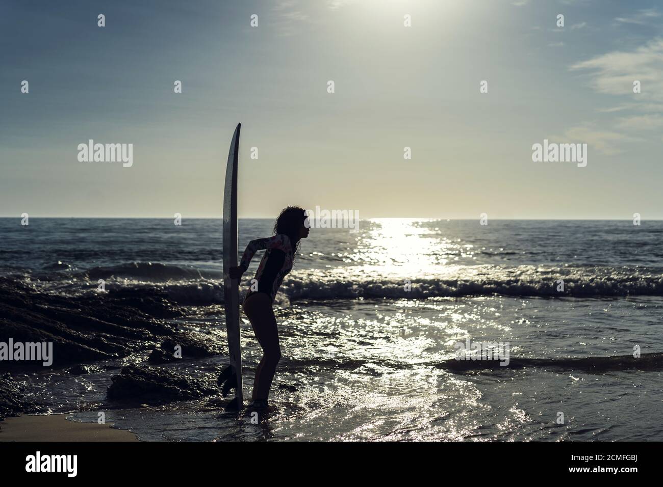 Beautiful young surfer woman with a surfboard having fun on the beach ...