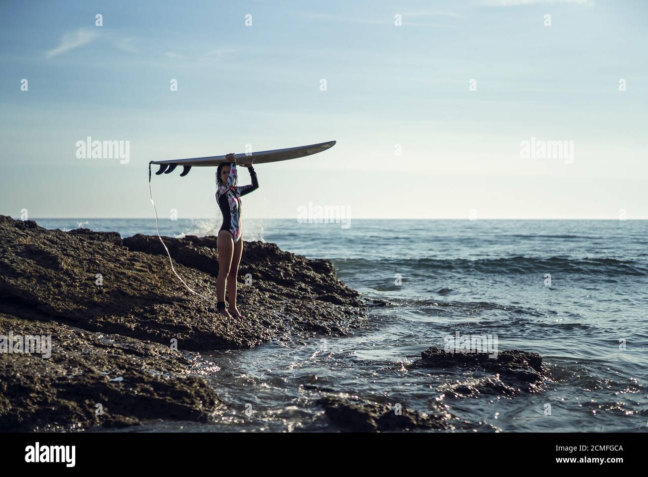 Beautiful young surfer woman with a surfboard having fun on the beach ...