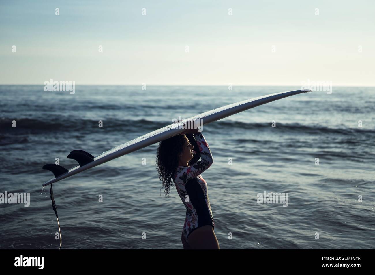 Beautiful young surfer woman with a surfboard having fun on the beach ...