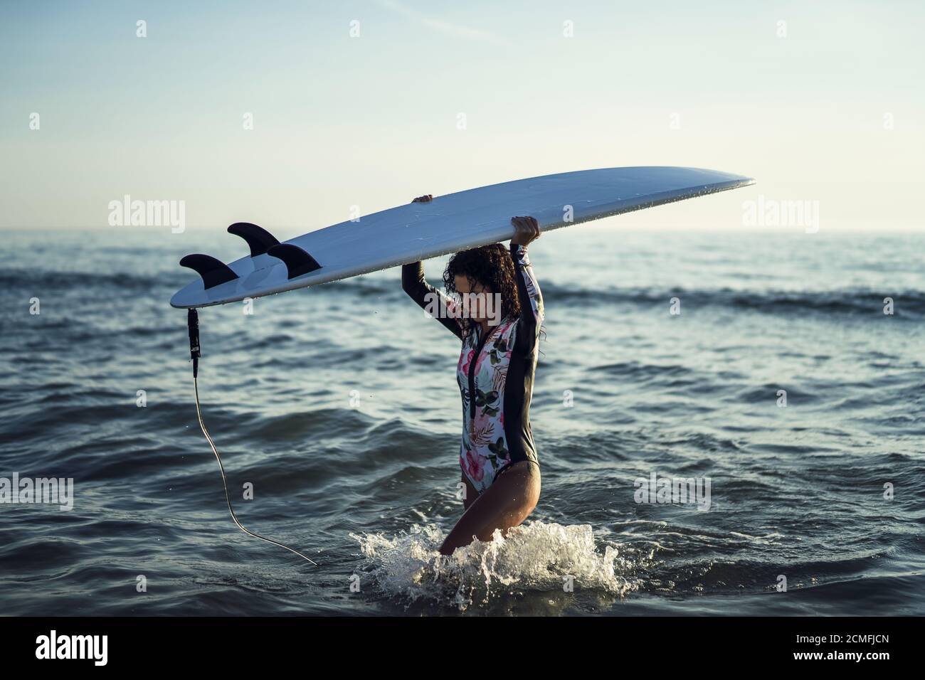 Beautiful young surfer woman with a surfboard having fun on the beach ...