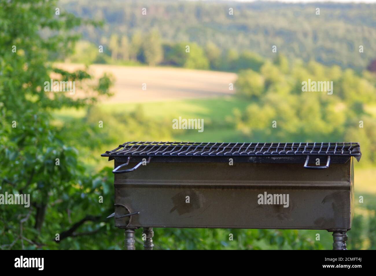 Empty portable BBQ grill in front of a fresh green summer landscape ...