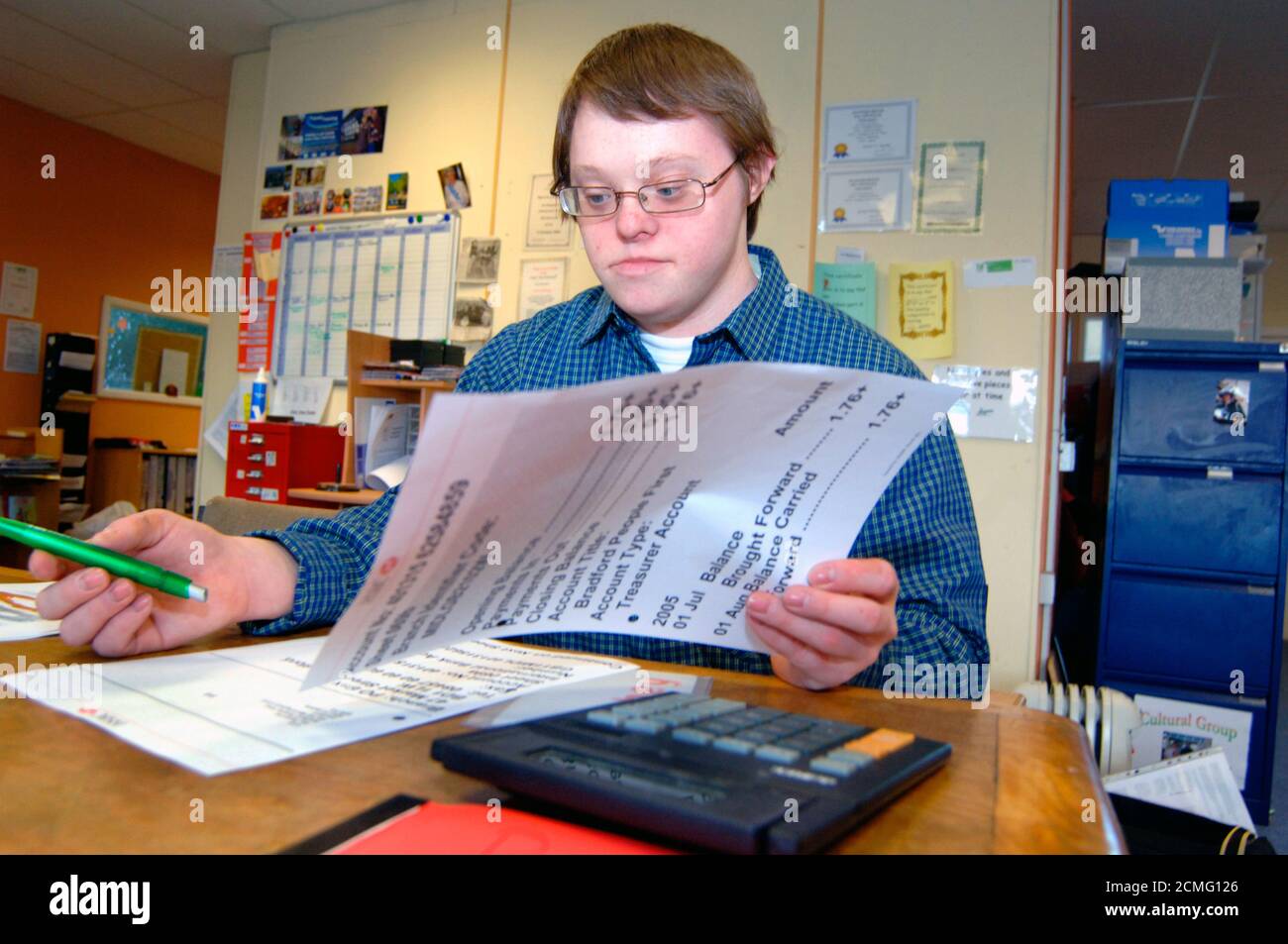 Young man with learning disabilities reading large print bank statement ...