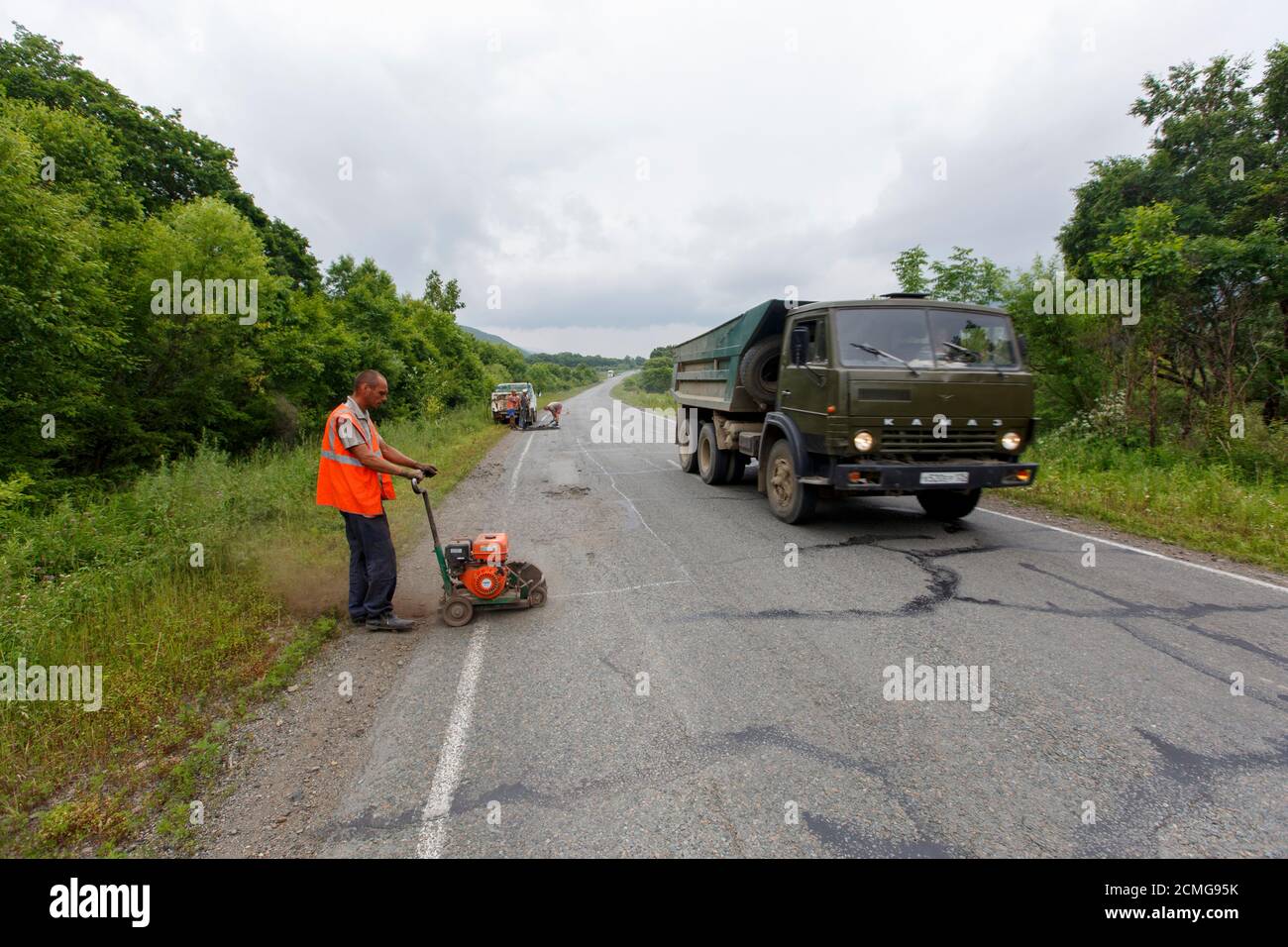 Repair of a bad road. Workers pave a bad road in a forest in Russia ...