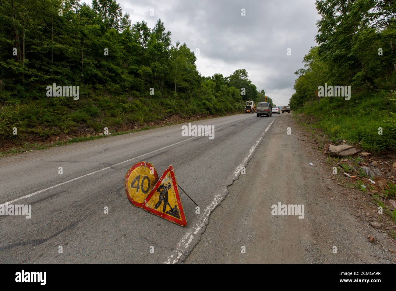 Repair of a bad road. Workers pave a bad road in a forest in Russia ...