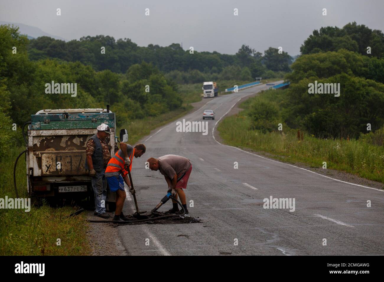 Repair of a bad road. Workers pave a bad road in a forest in Russia ...