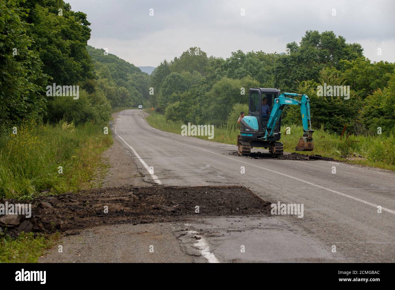 Repair of a bad road. Workers pave a bad road in a forest in Russia ...