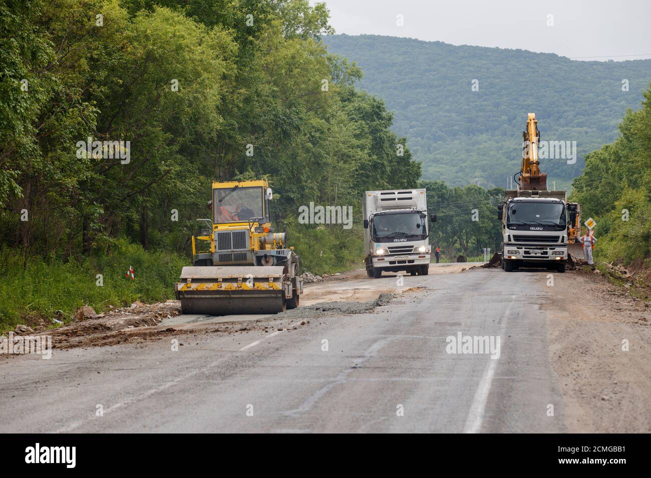 Repair of a bad road. Workers pave a bad road in a forest in Russia ...