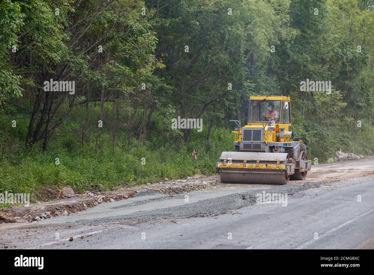 Repair of a bad road. Workers pave a bad road in a forest in Russia ...