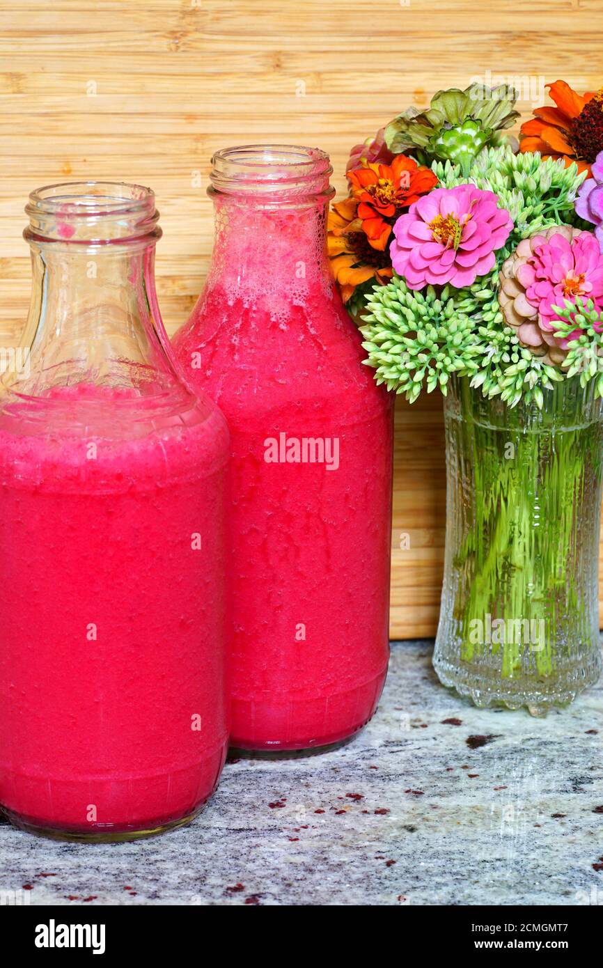 Glass bottles filled with colorful fresh homemade beet and peach ...