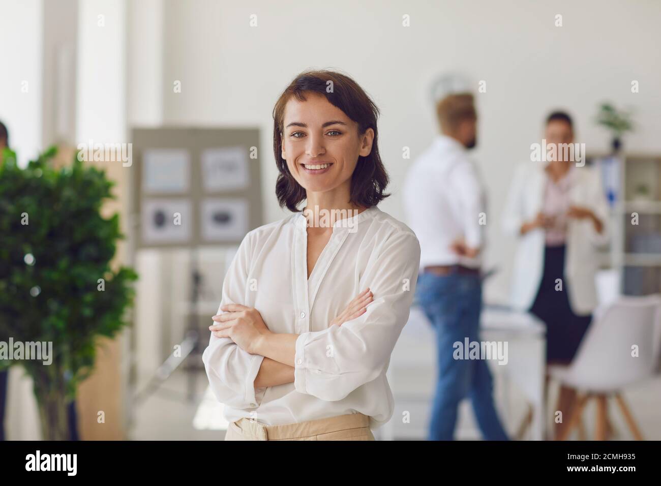 Happy successful business lady or company employee standing in office ...