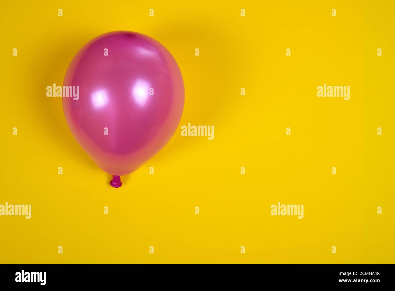 Inflated pink air balloon on the yellow surface Stock Photo - Alamy